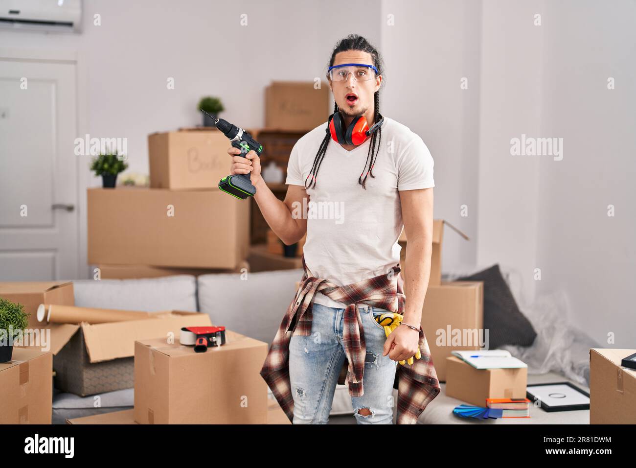 Hispanic man with long hair holding screwdriver at new home scared and ...