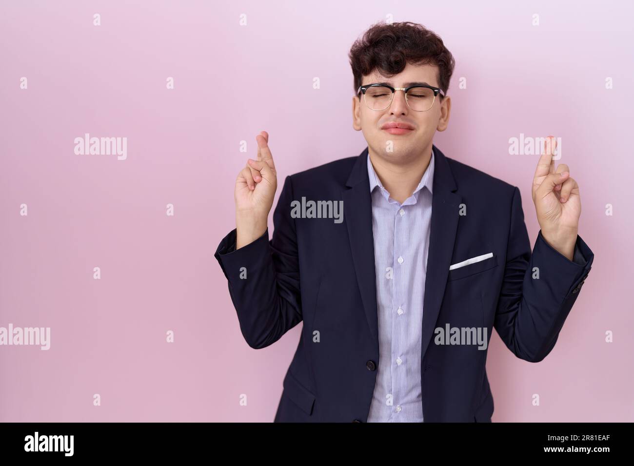 Young non binary man with beard wearing suit and tie gesturing finger ...
