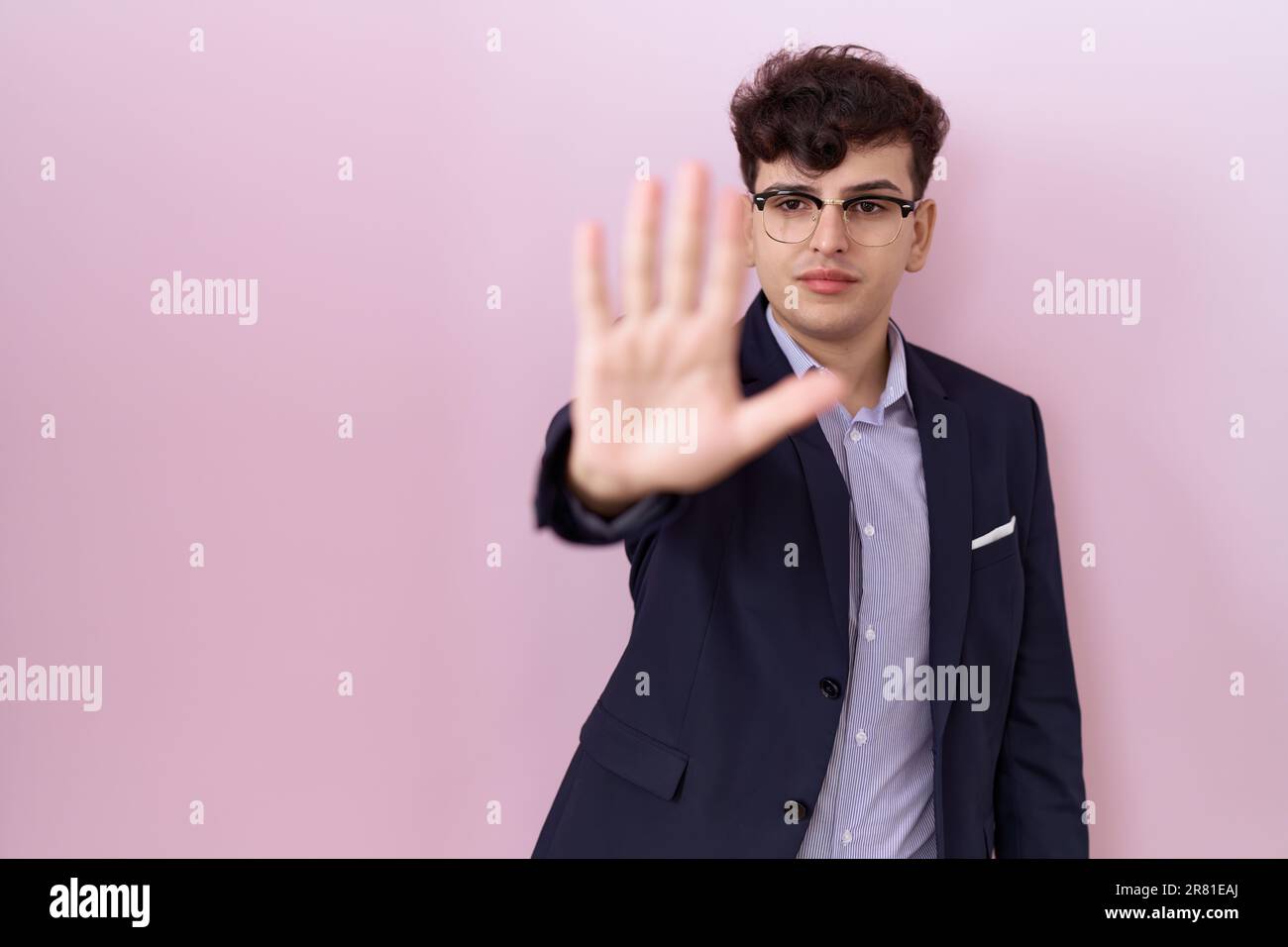 Young non binary man with beard wearing suit and tie doing stop sing ...