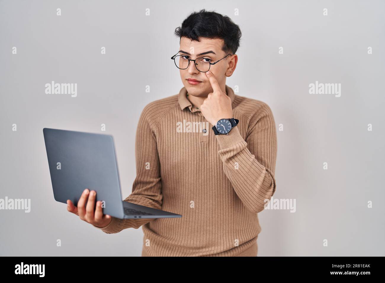 Non binary person using computer laptop pointing to the eye watching ...