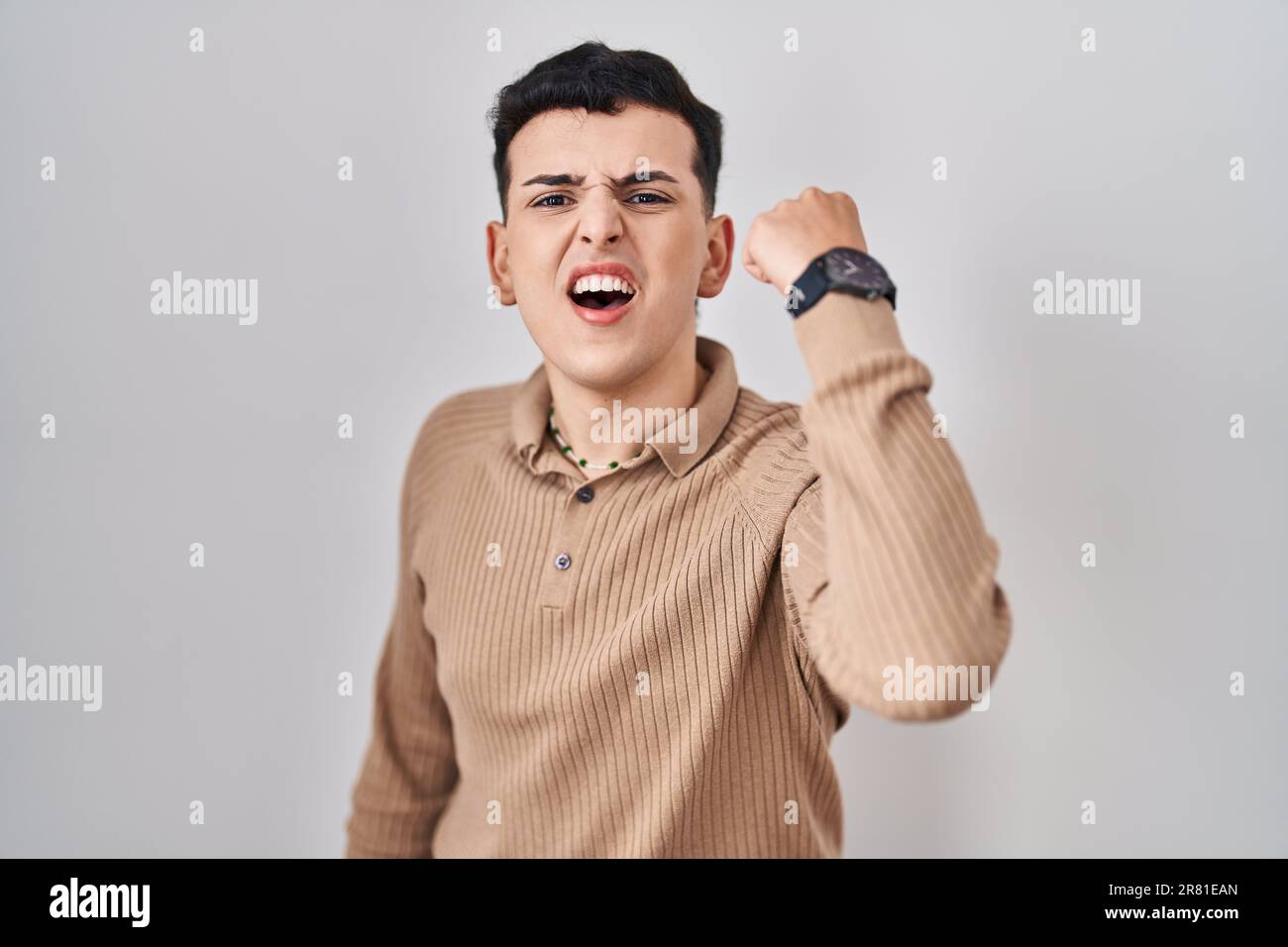 Non binary person standing over isolated background angry and mad ...