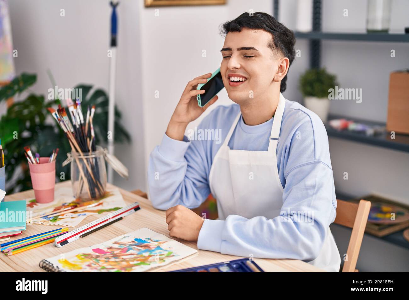 Young non binary man artist smiling confident talking on the smartphone ...