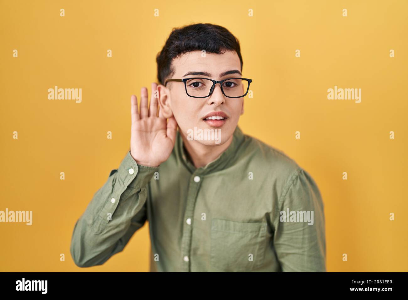 Non binary person standing over yellow background smiling with hand ...