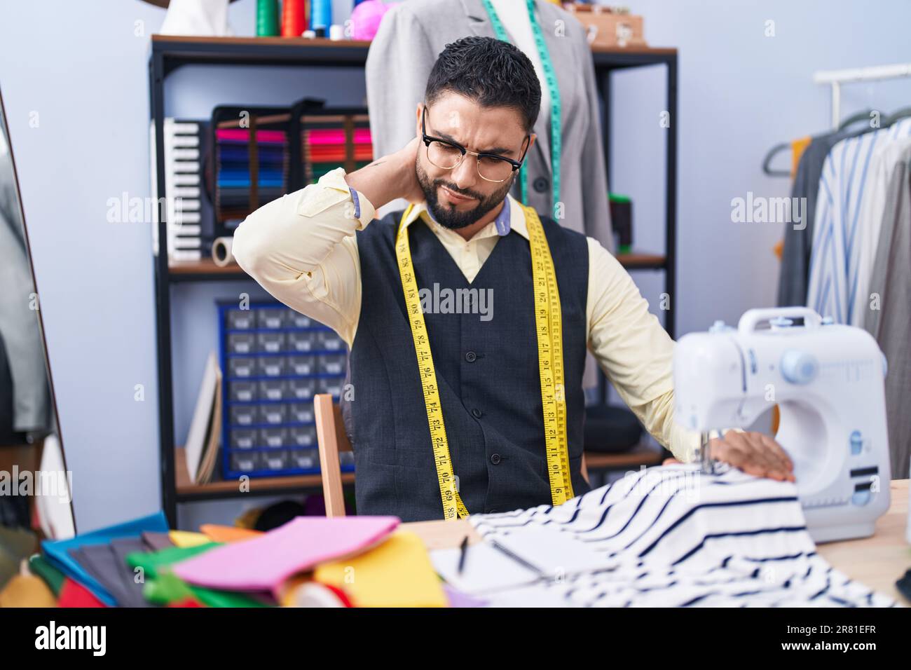 Young arab man tailor stressed using sewing machine at clothing factory ...