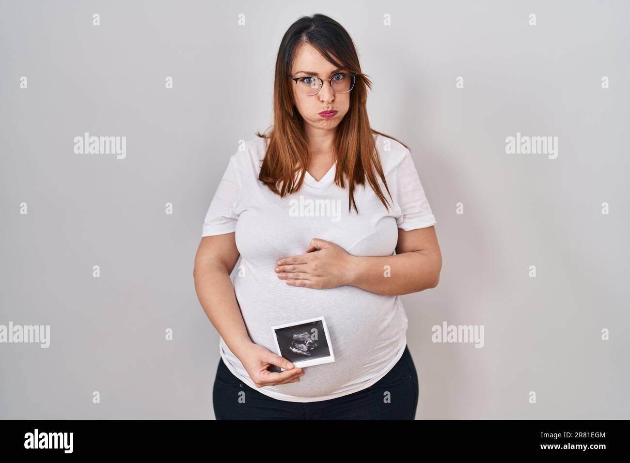 Pregnant woman holding baby ecography puffing cheeks with funny face ...