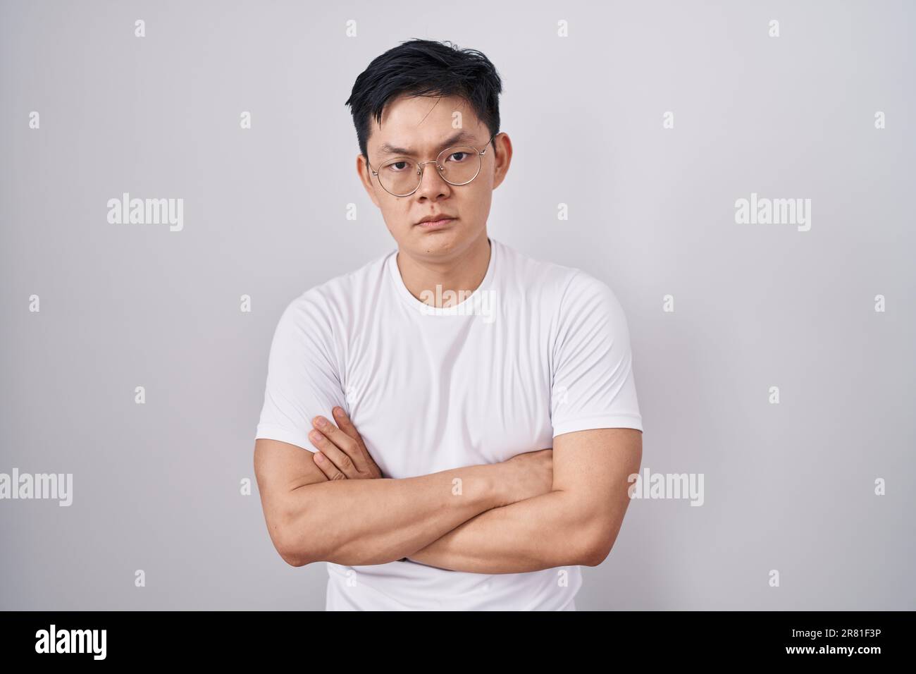 Young asian man standing over white background skeptic and nervous ...