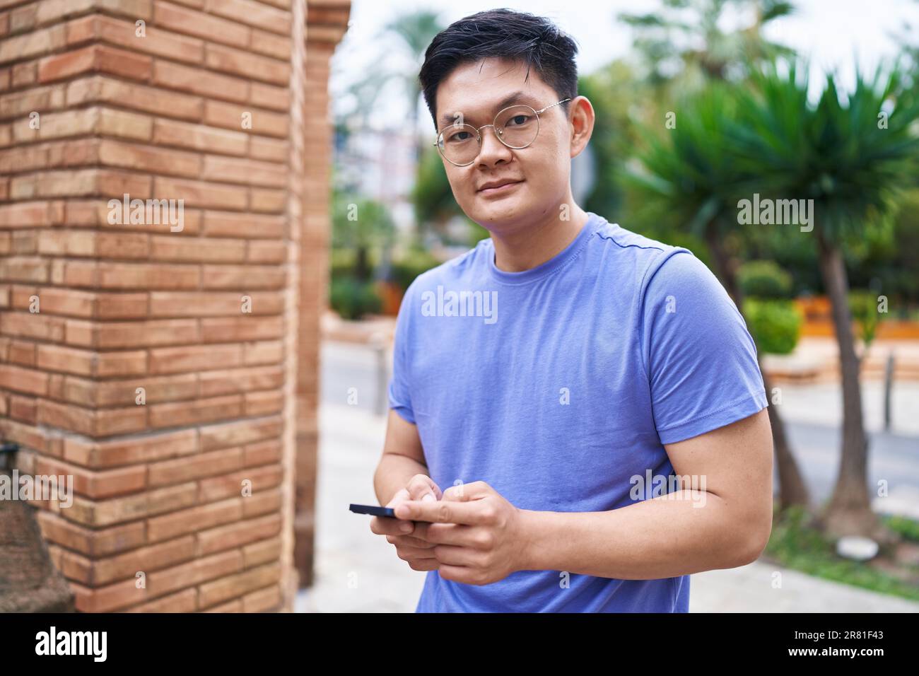 Young chinese man smiling confident using smartphone at street Stock ...