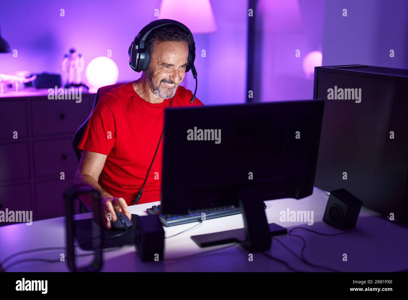 Middle age man streamer playing video game using computer at gaming ...