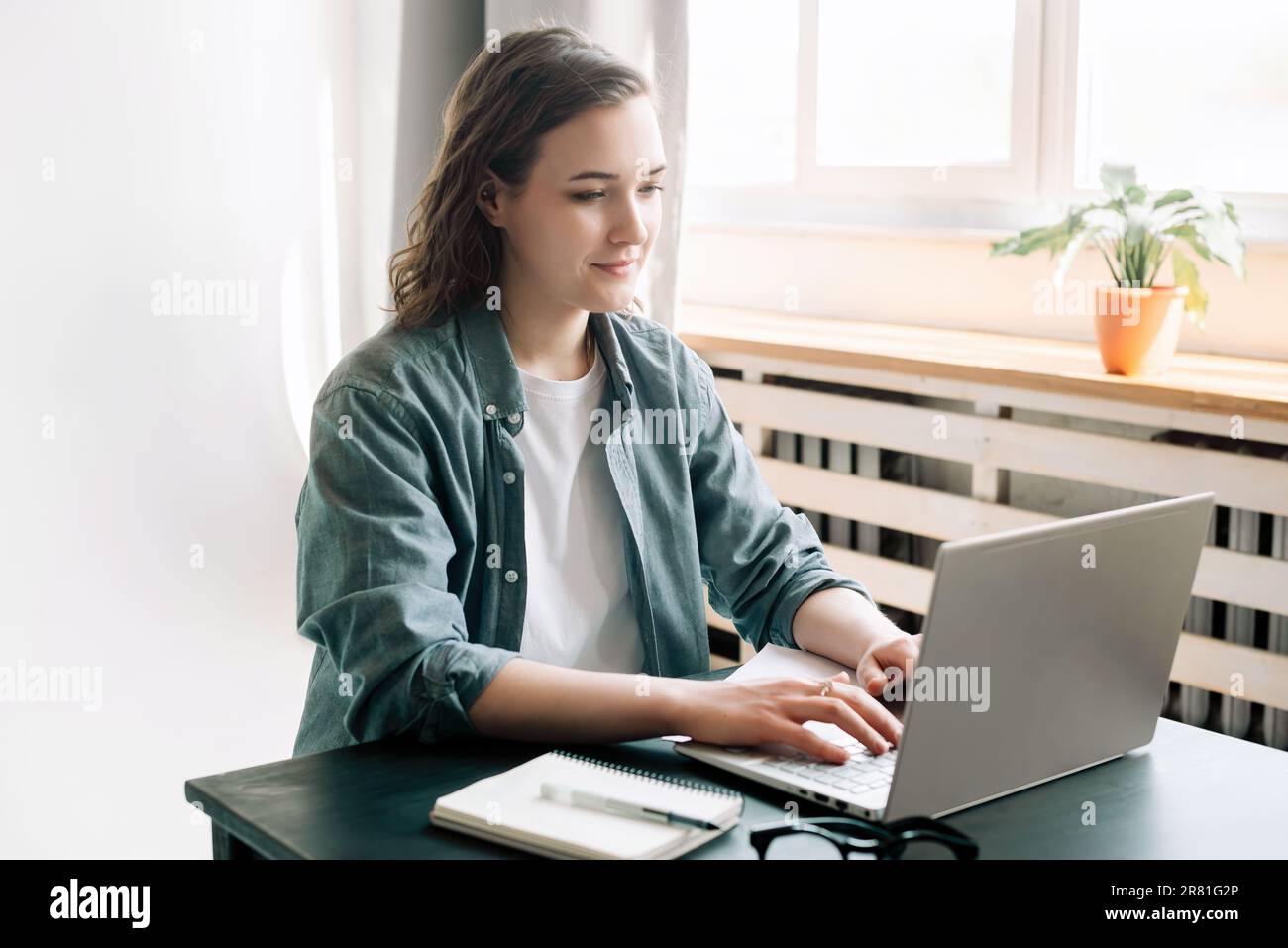 Young woman multitasking with a laptop in a modern office environment ...