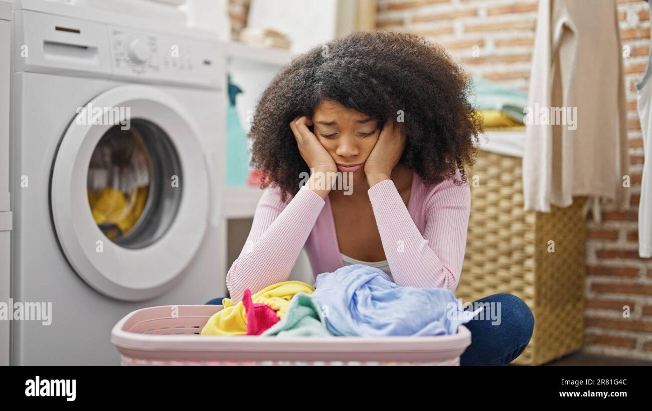 African american woman washing clothes looking upset at laundry room ...