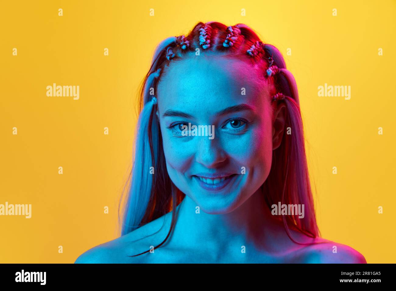 Portrait of cute young girl with pretty hairstyle looking at camera ...