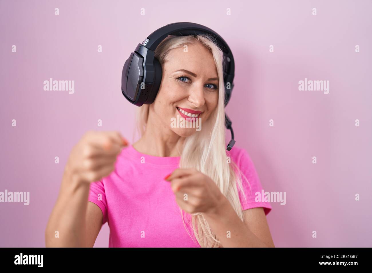 Caucasian woman listening to music using headphones pointing fingers to ...