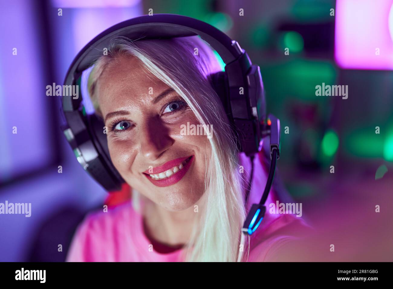 Young blonde woman streamer wearing headphones make selfie by camera at ...