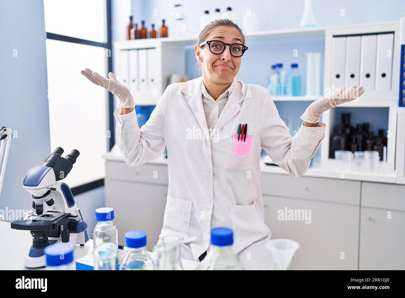 Young woman working at scientist laboratory shouting and screaming loud ...