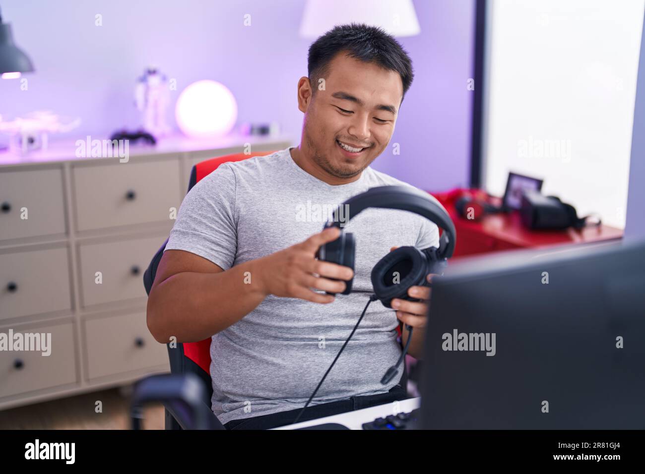 Young chinese man streamer smiling confident holding headphones at ...