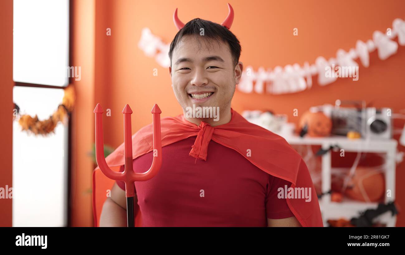 Young chinese man wearing devil costume holding trident at home Stock ...