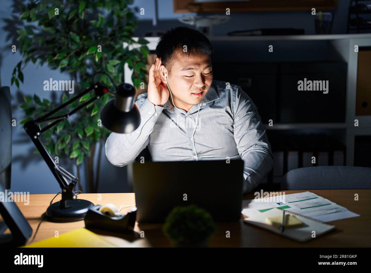 Young chinese man working using computer laptop at night smiling with ...