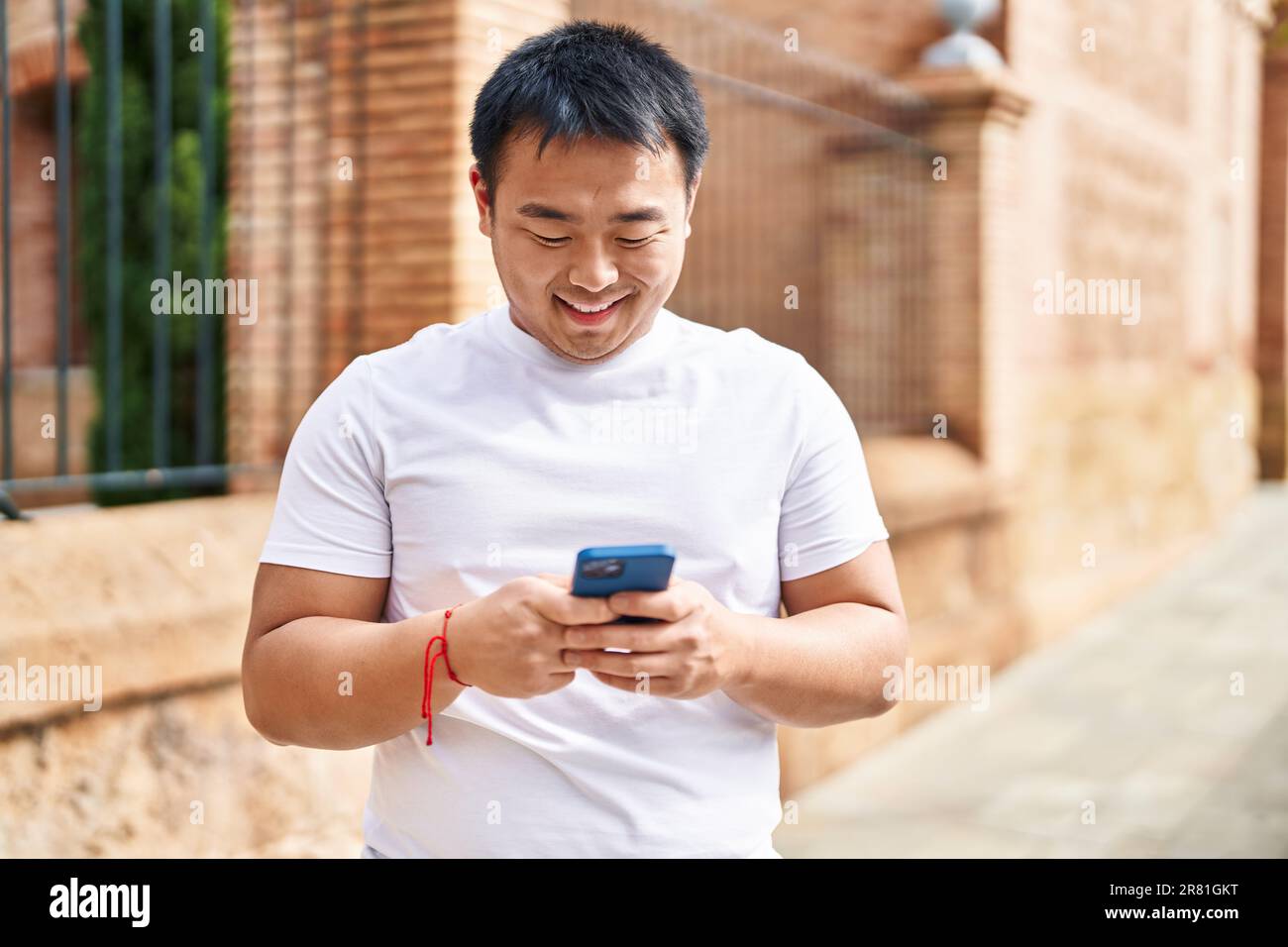 Young chinese man smiling confident using smartphone at street Stock ...