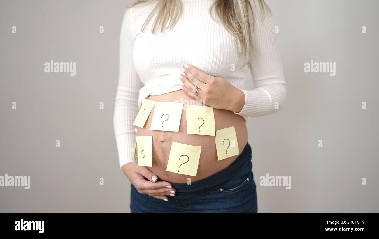 Young pregnant woman putting question mark reminder paper on belly ...