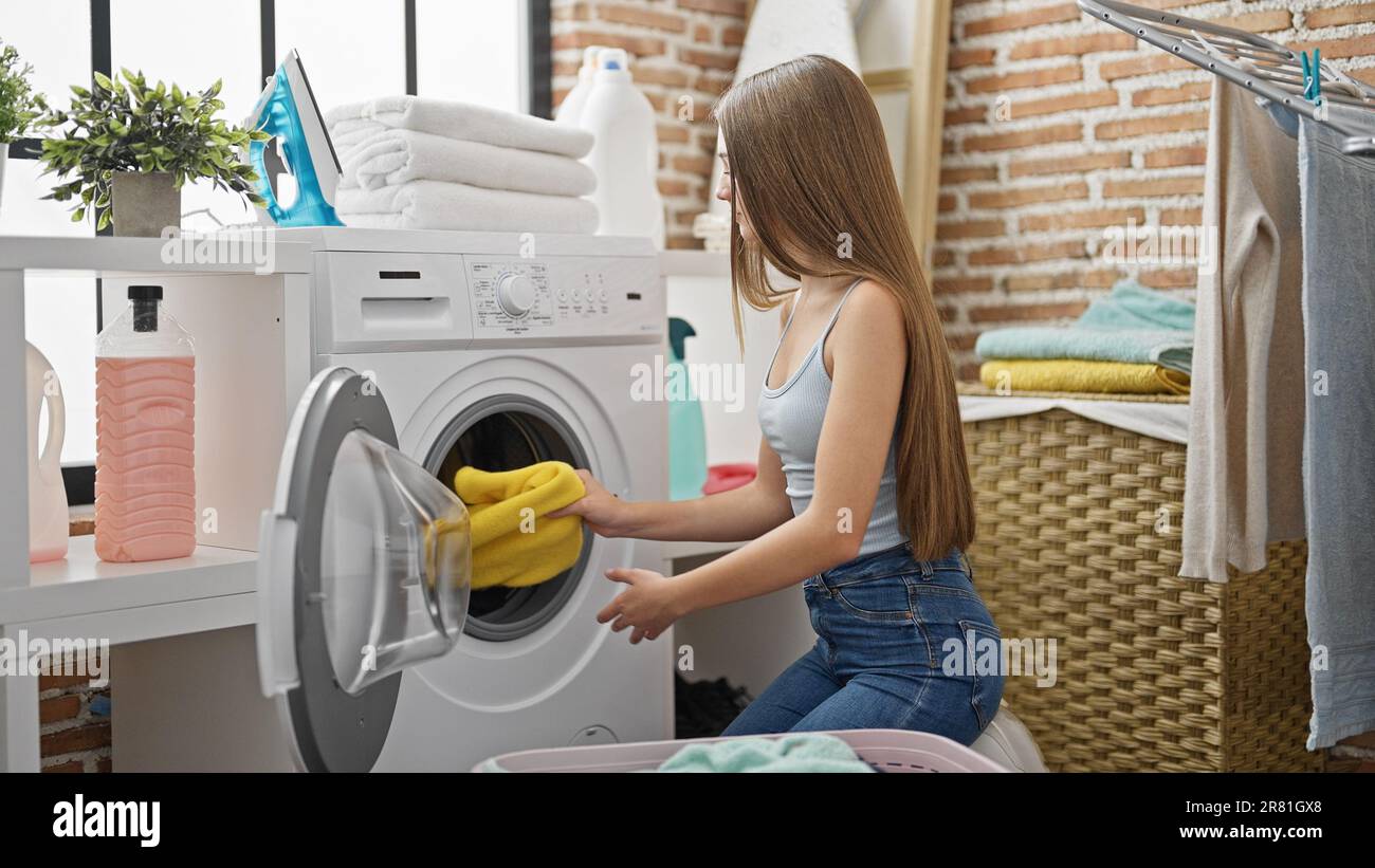 Young beautiful girl washing clothes at laundry room Stock Photo - Alamy