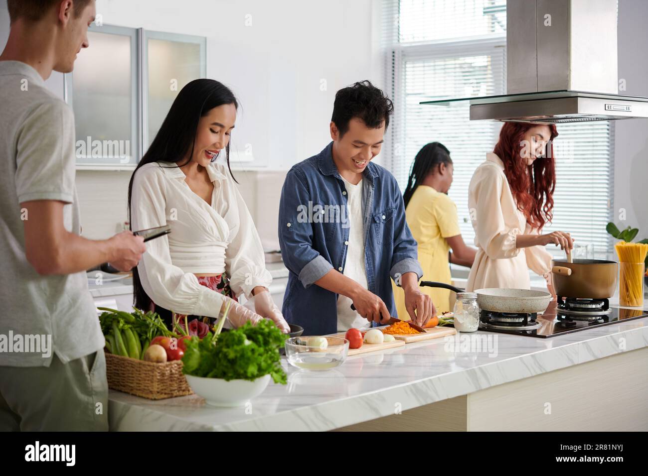Group of friends cooking dinner together at kitchen counter Stock Photo ...