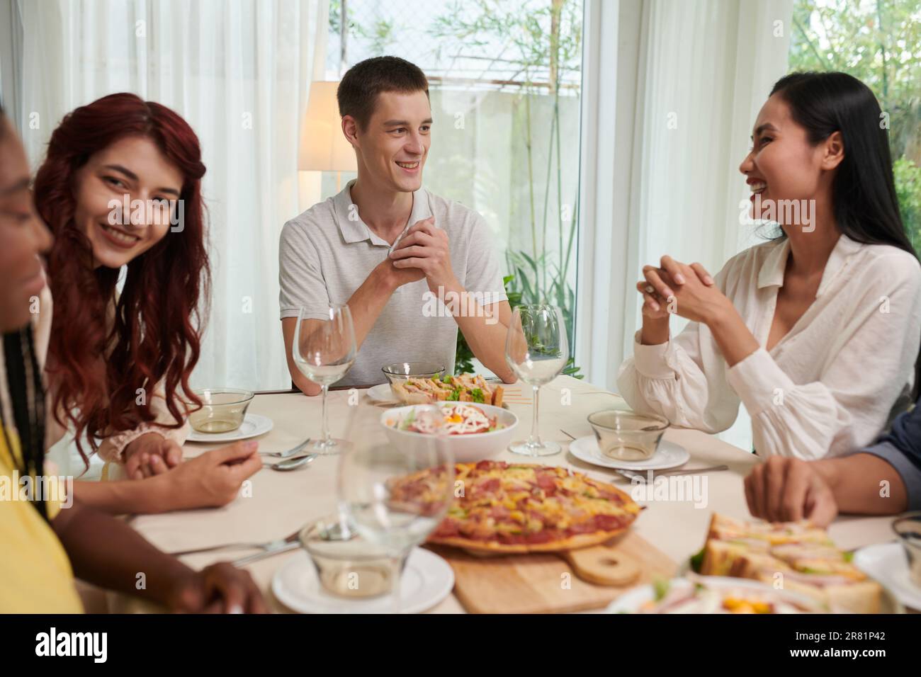 Group of happy friendly young people talking at dinner table Stock ...