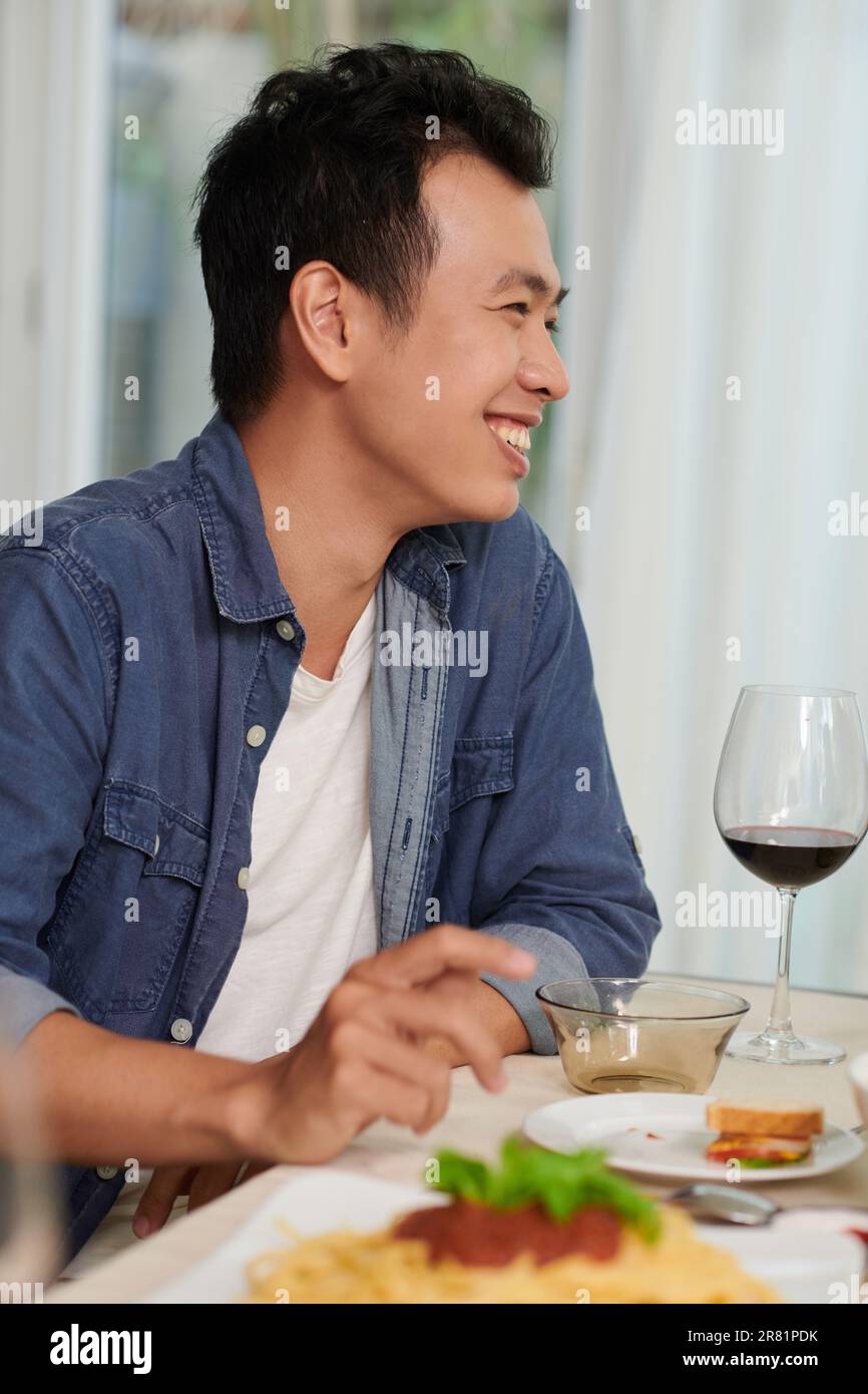 Joyful Vietnamese man talking to friends at dinner party Stock Photo ...