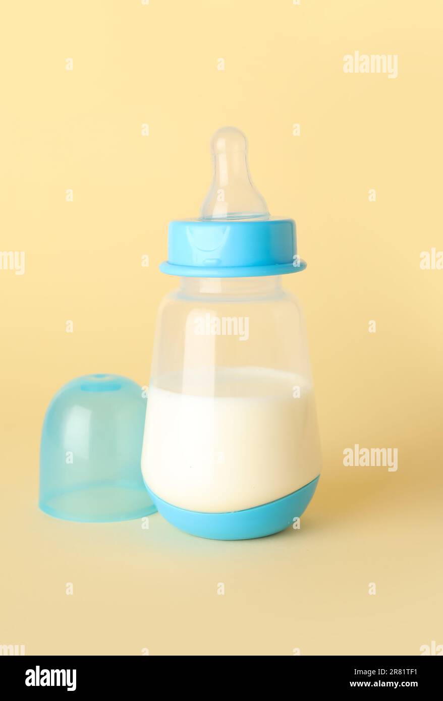 Bottle with milk for baby on pale yellow background Stock Photo - Alamy