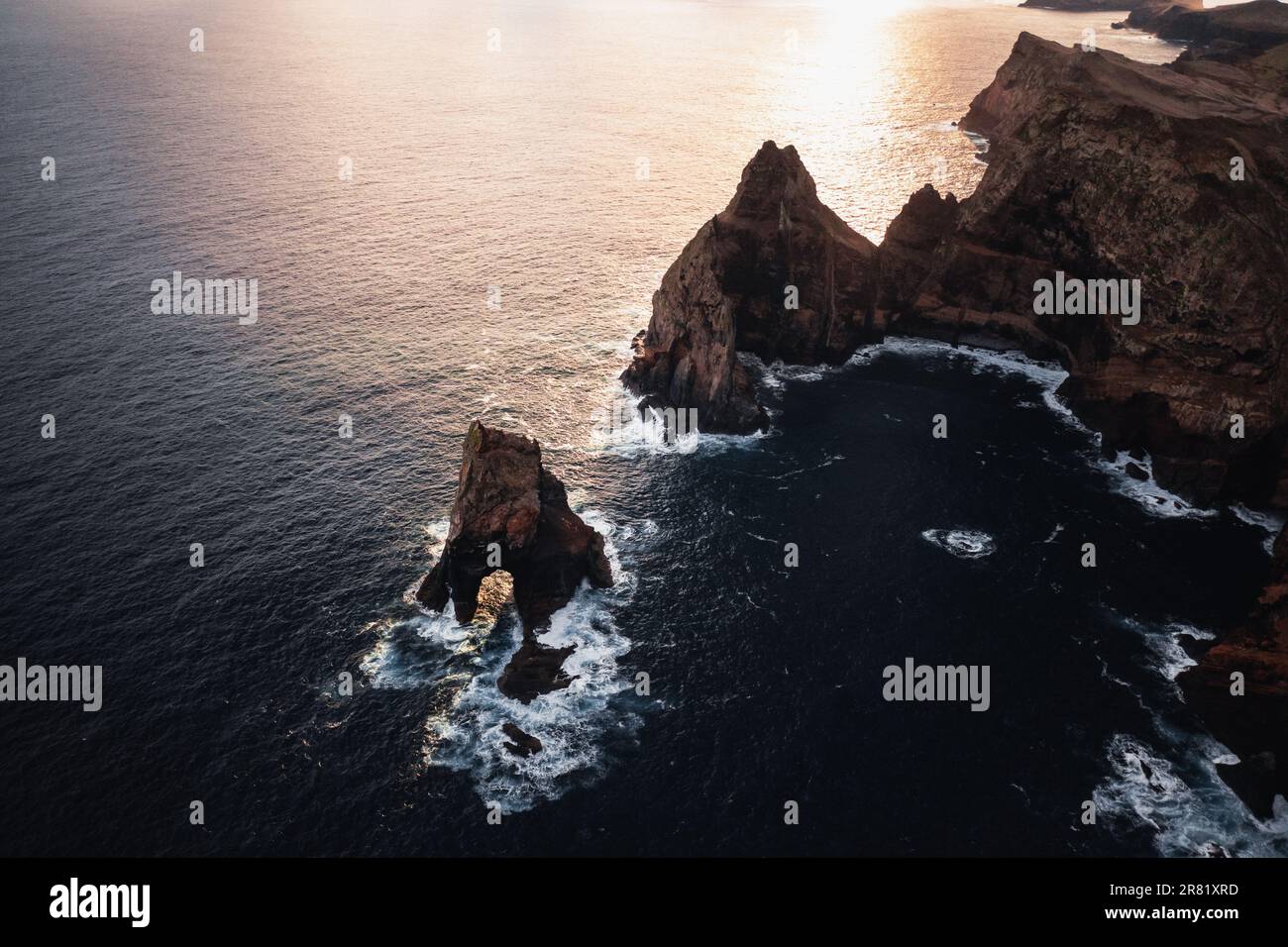 A tranquil scene of an expansive body of water, edged by jagged rocks ...