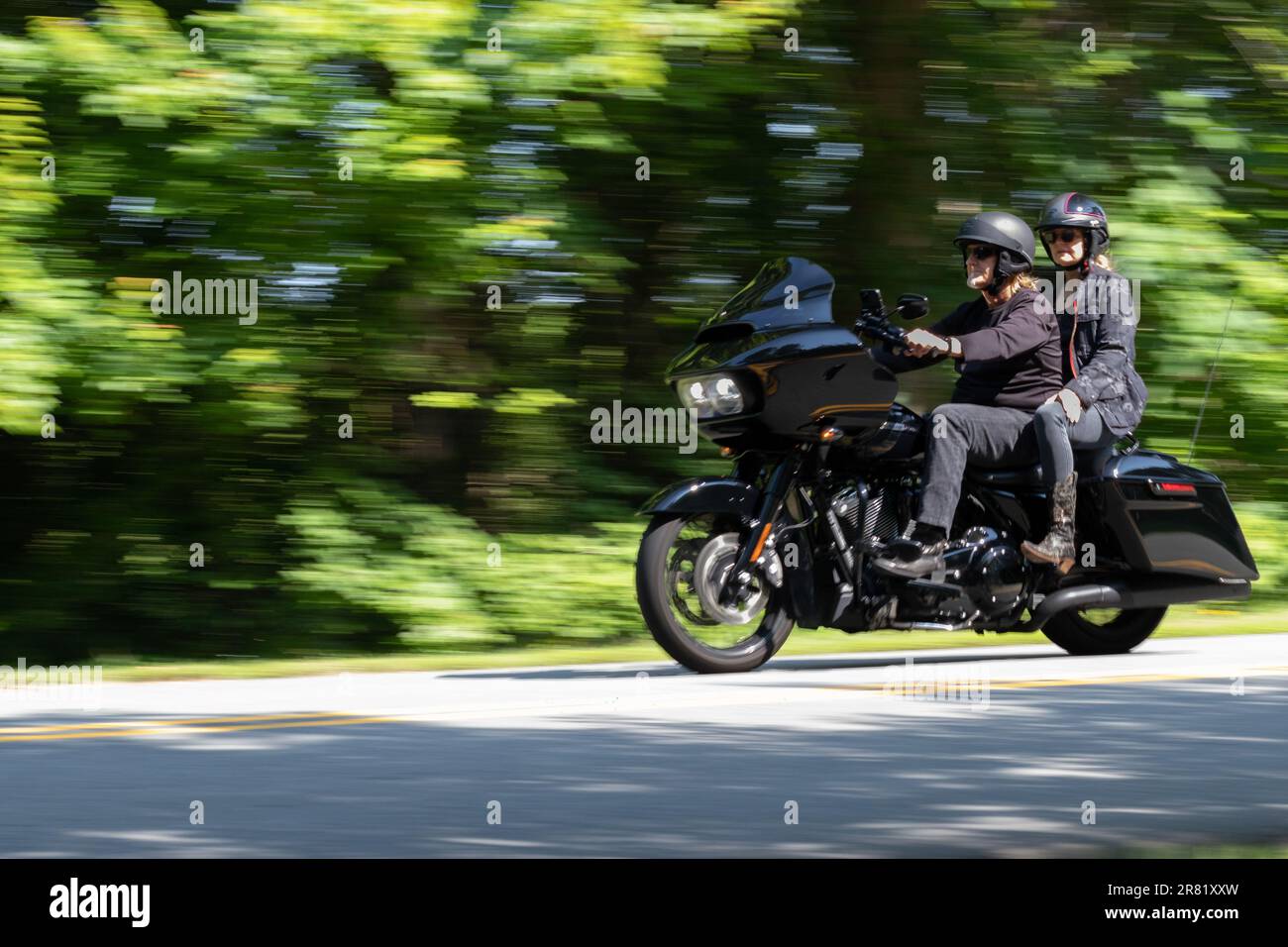 panning photo of black motorcycle with two riders showing motion Stock ...
