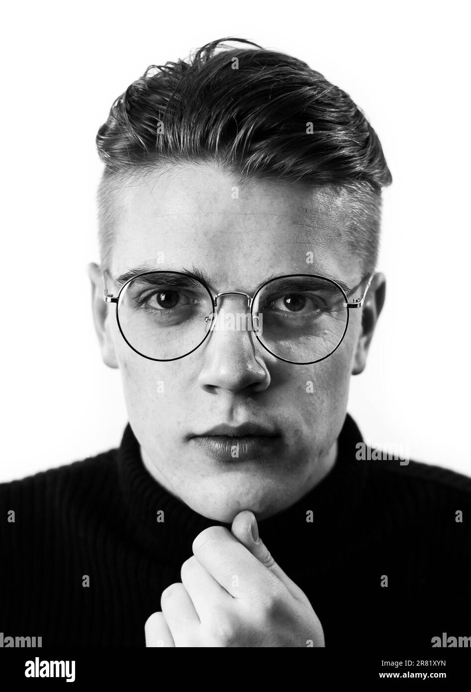 A grayscale of a mature man wearing glasses looks directly at the ...