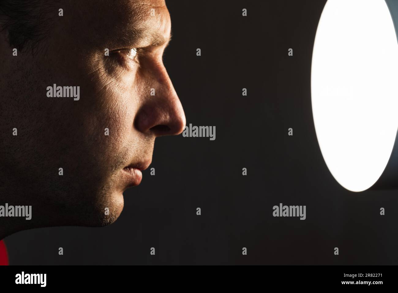 Close-up profile portrait of young European man staring at the light ...