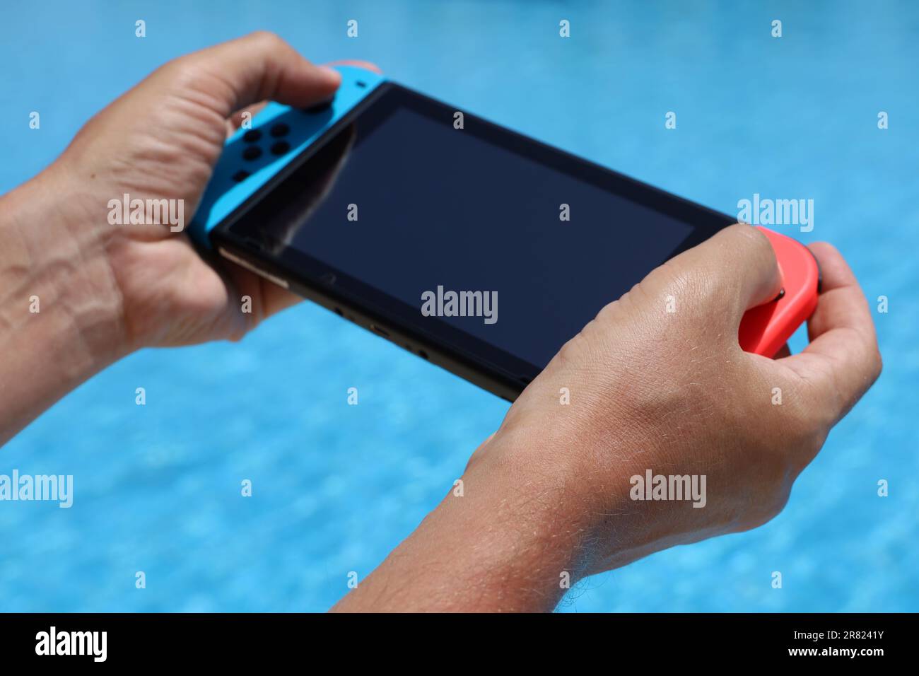 Man playing game on handheld console in swimming pool, selective focus ...