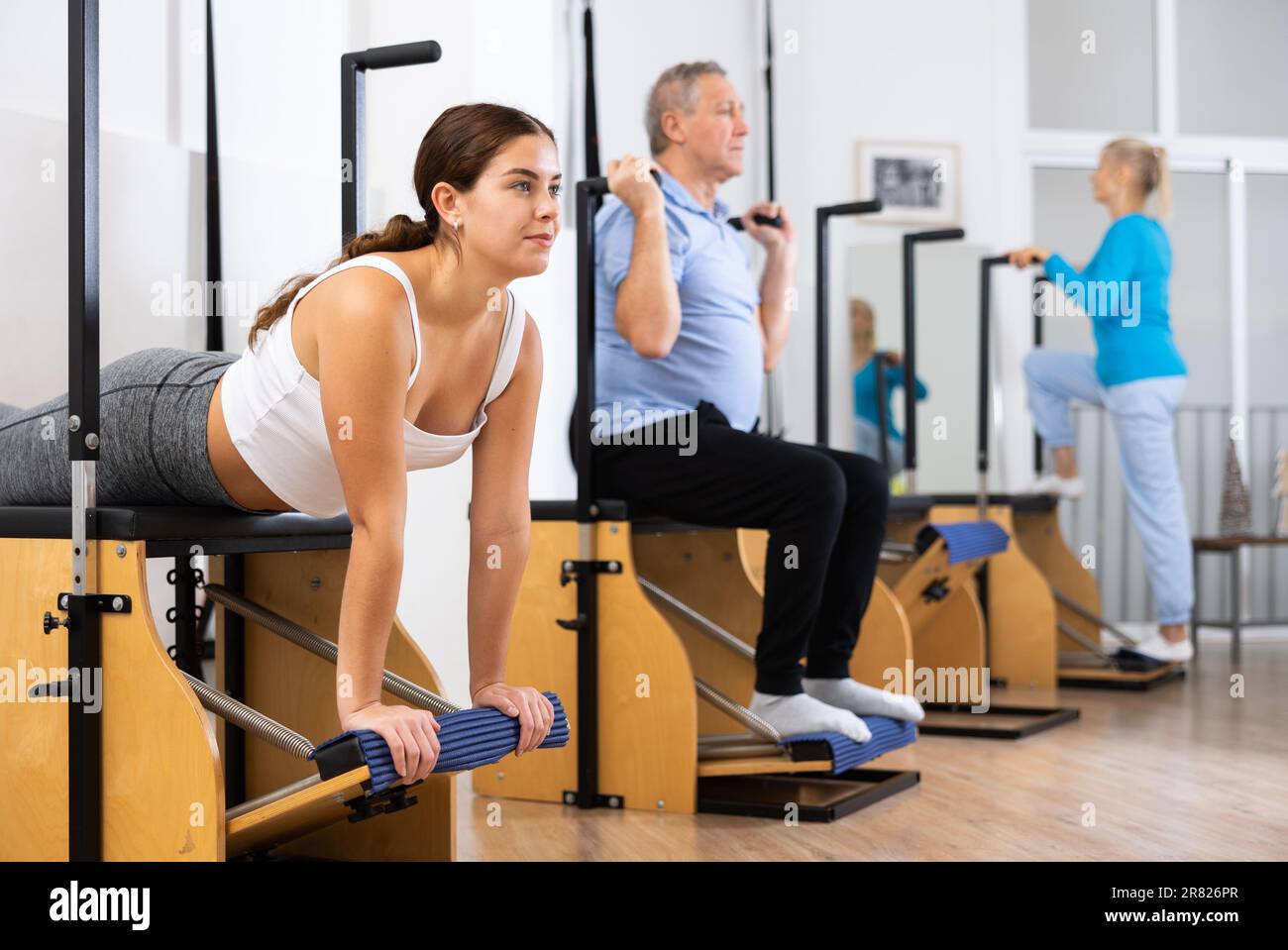 Young European woman training lower back on Pilates Wanda chair machine ...