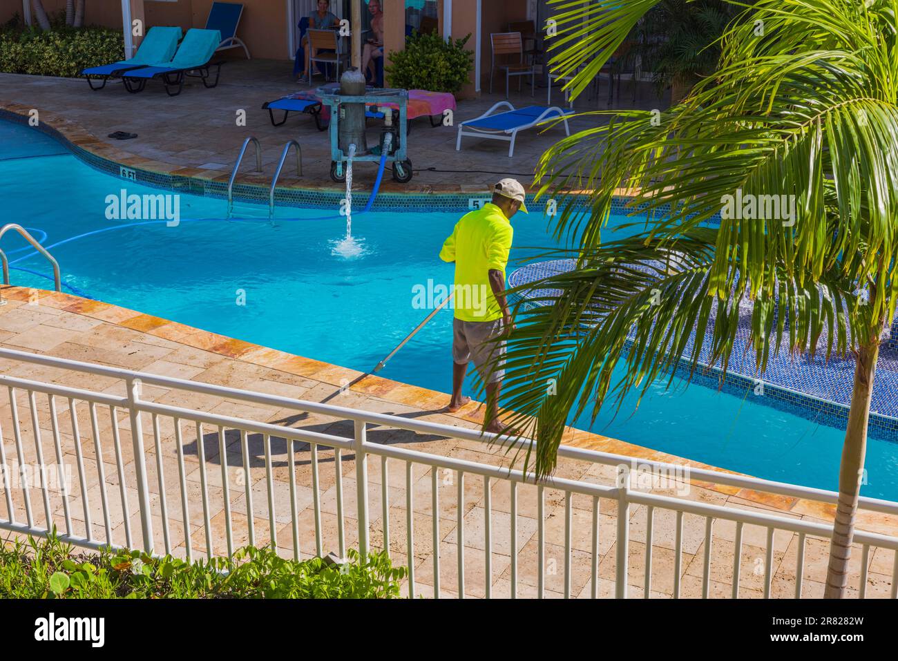 Close up view of hotel employee cleaning outdoor pool. Aruba ...