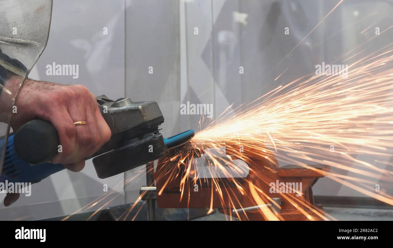 Worker cutting metal with grinder. Sparks while grinding iron. Electric ...