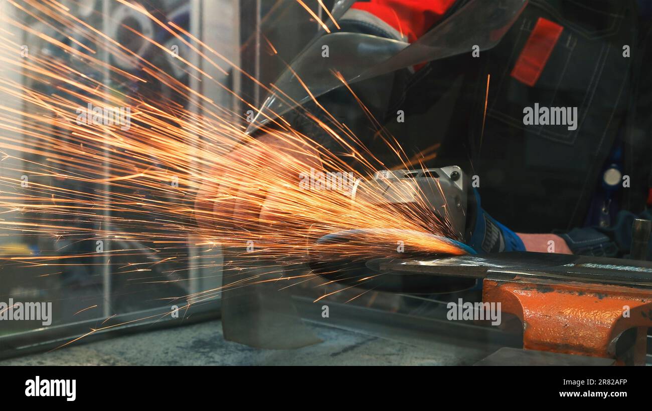 Worker cutting metal with grinder. Sparks while grinding iron. Electric ...