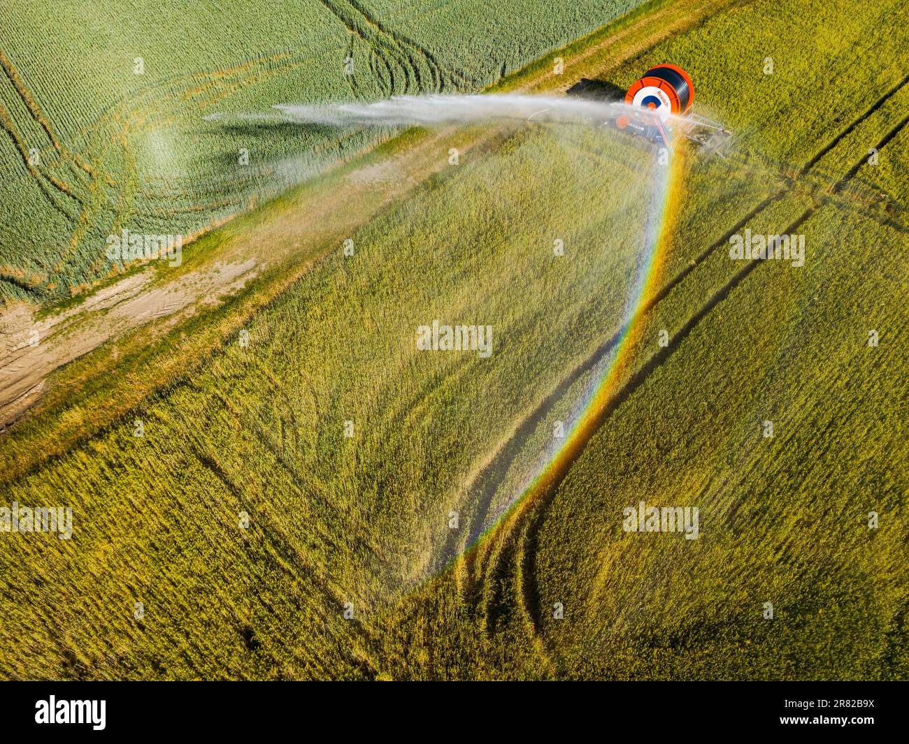 Irrigation system on a field with water jet and rainbow seen from above ...