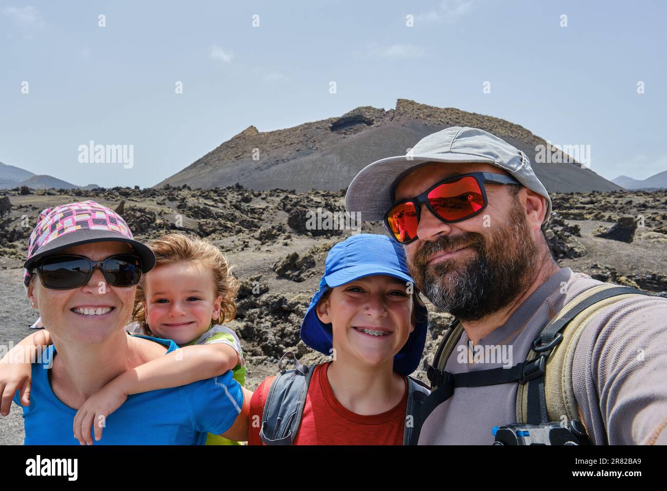 Family taking a selfie while hiking between volcanoes. El Cuervo volcano in the background ...