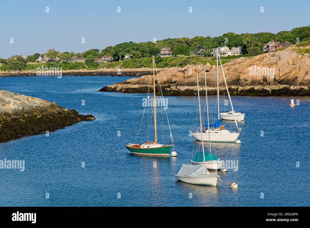Sailboats moored in Rockport harbor channel delineated by rock ...