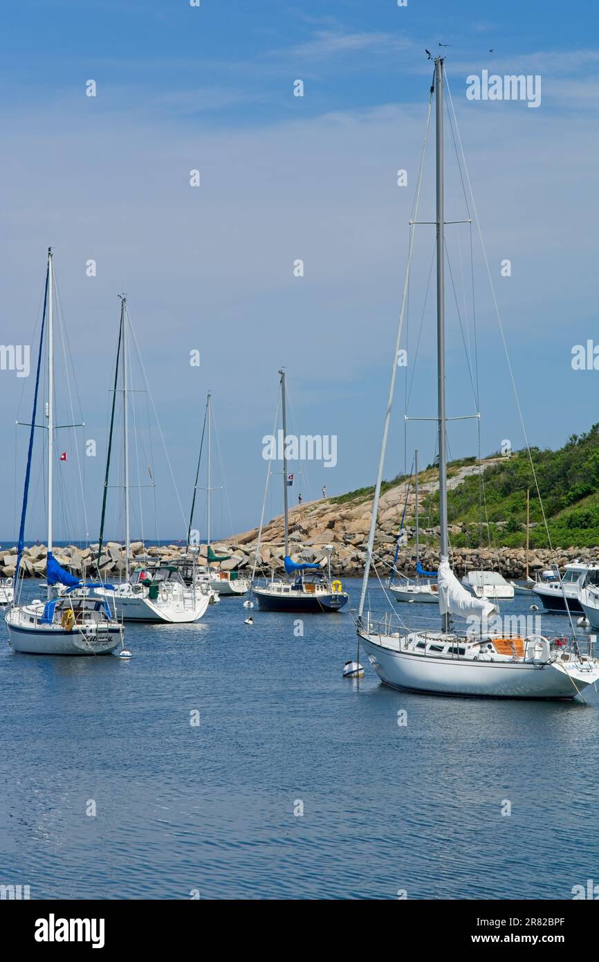 Sailboats moored in Rockport harbor channel lined by stone jetty and ...