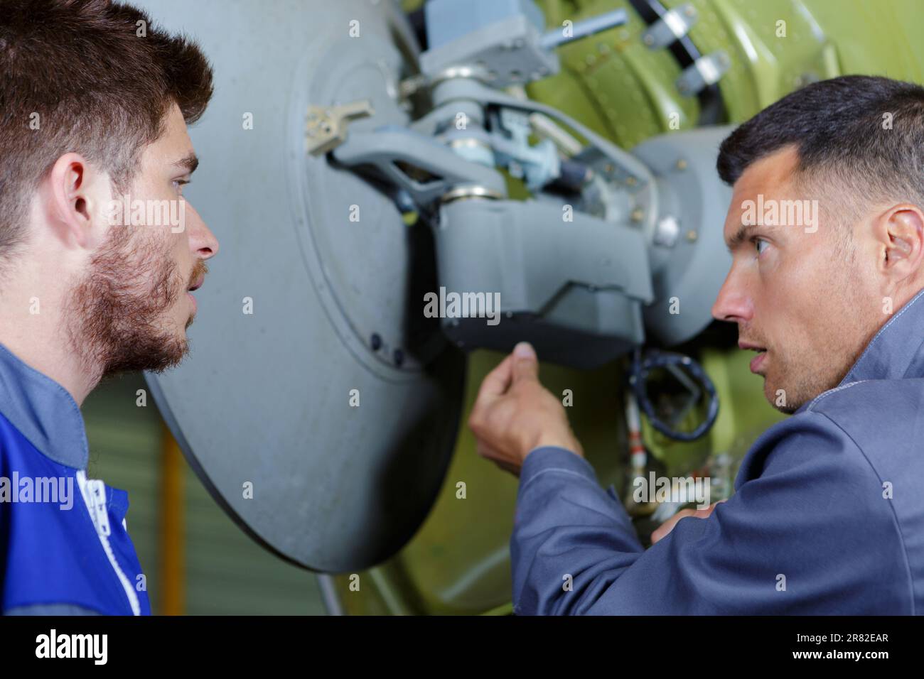 two mechanics working on a metal object Stock Photo - Alamy