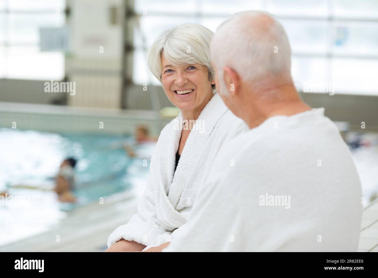 elderly couple wearing bathrobes sat by indoor pool Stock Photo - Alamy