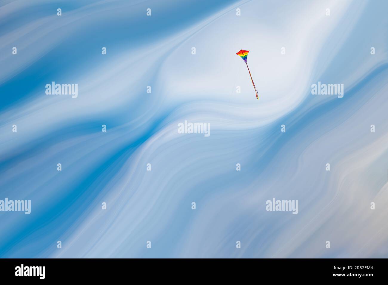 Rainbow kite against a blue cloudy sky, and the sky is streaked after ...