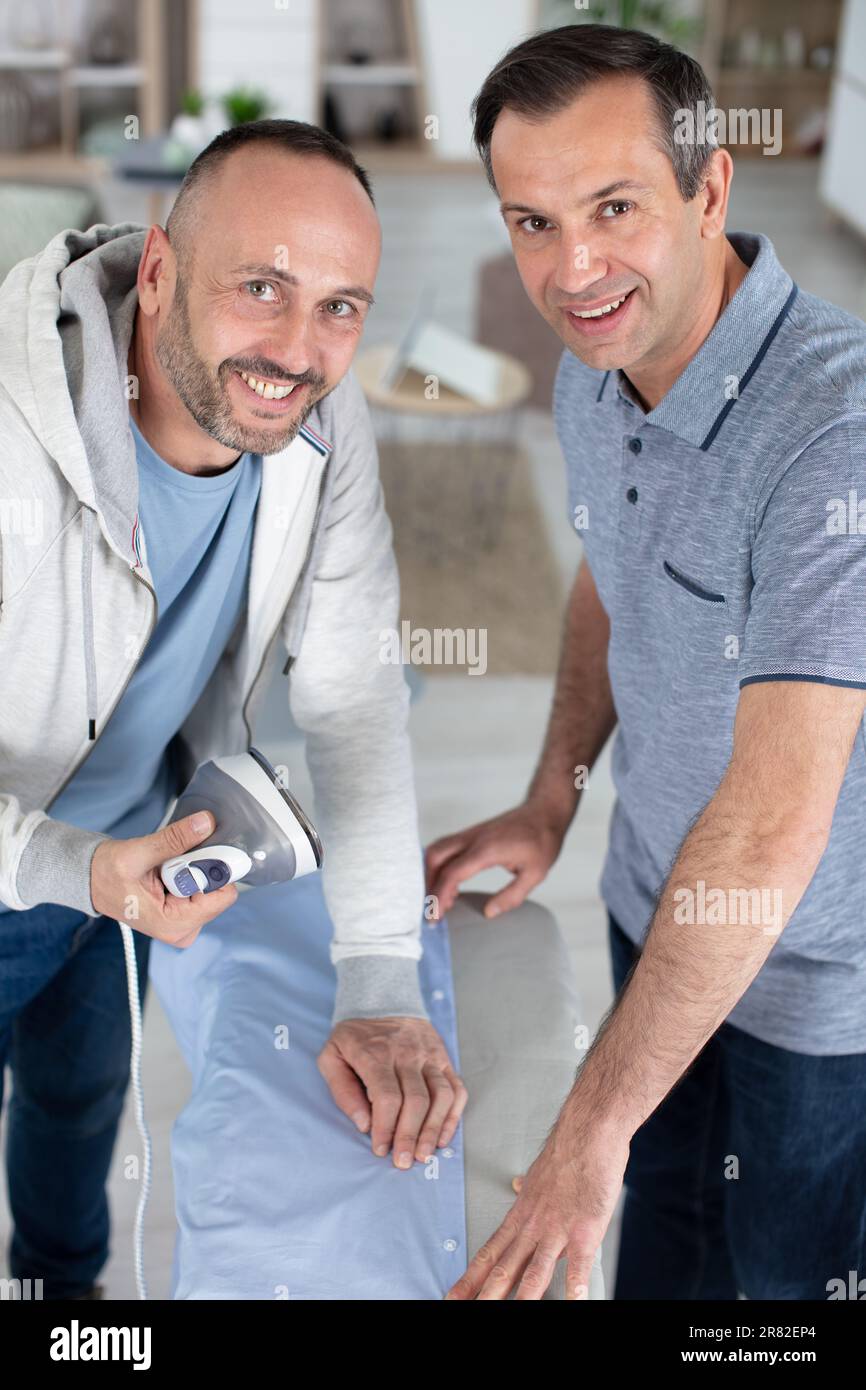 two middle aged men stood by the ironing board Stock Photo - Alamy
