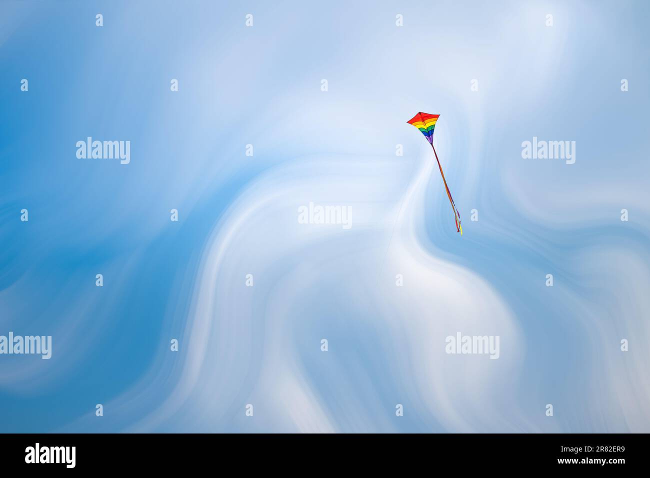 Rainbow kite against a blue cloudy sky, and the sky is streaked after ...