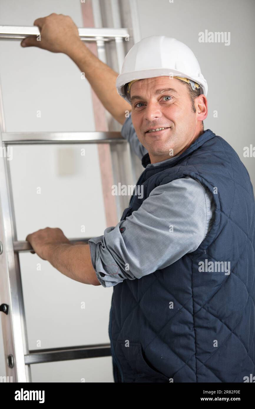 portrait of workman with hands on rungs of a ladder Stock Photo - Alamy