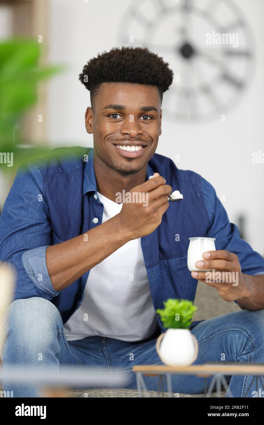 a young man eating yogurt Stock Photo - Alamy
