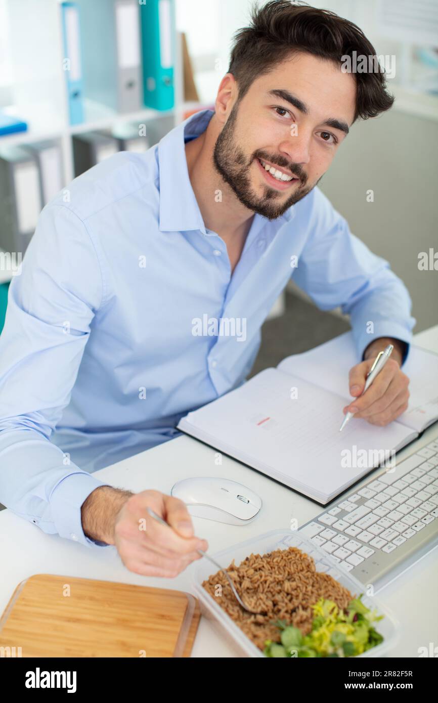 funny surprised office employee eating food while working Stock Photo ...