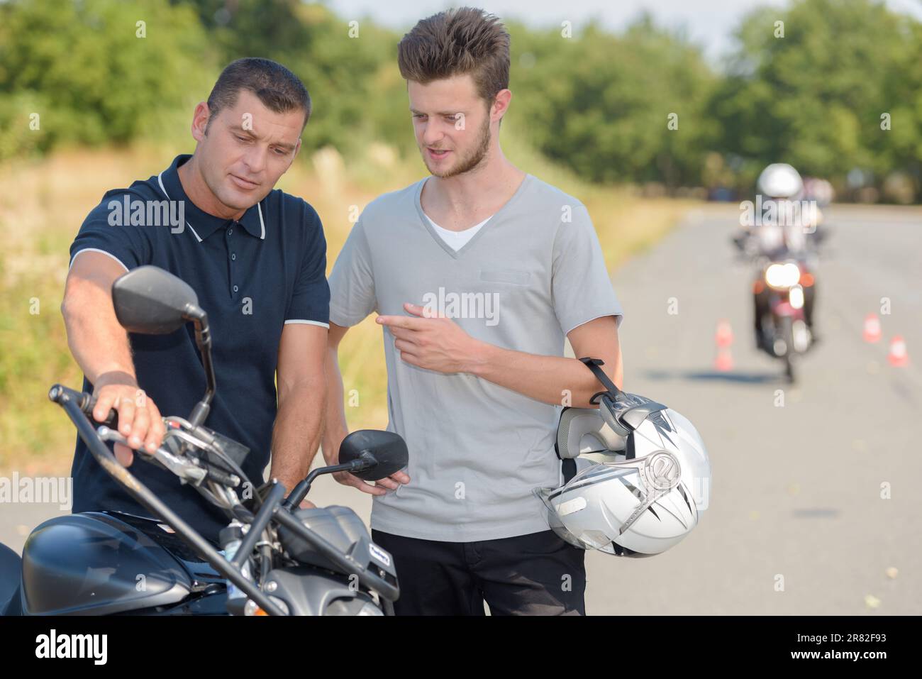 motorcycle driving instructor explaining handlebar controls to young ...